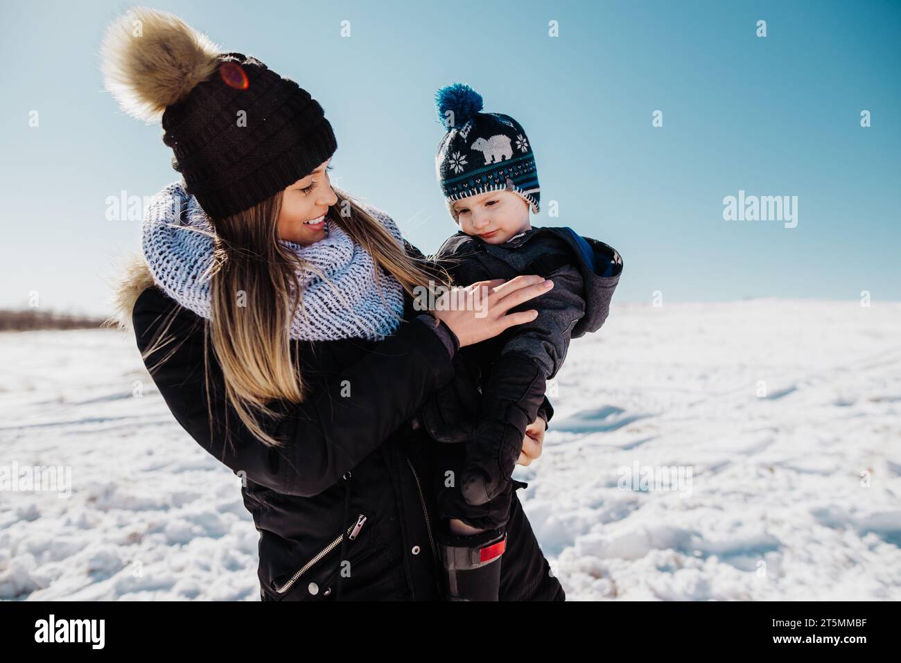 Woman smiles lovingly at child while wearing winter gear and hat Stock ...