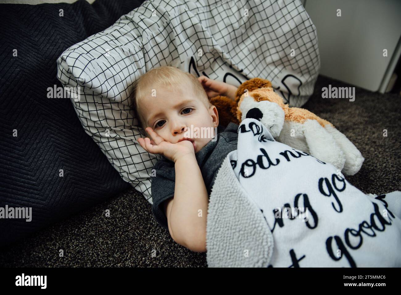 Side view of little boy laying on floor with a pillow and stuff Stock ...