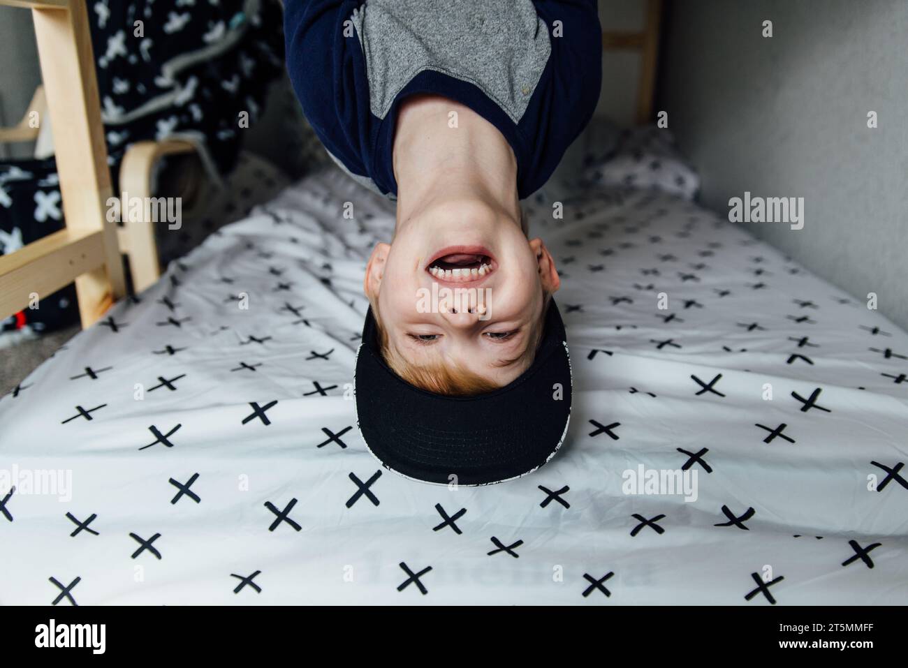 Close up of young boy hanging upside down and laughing off of be Stock ...
