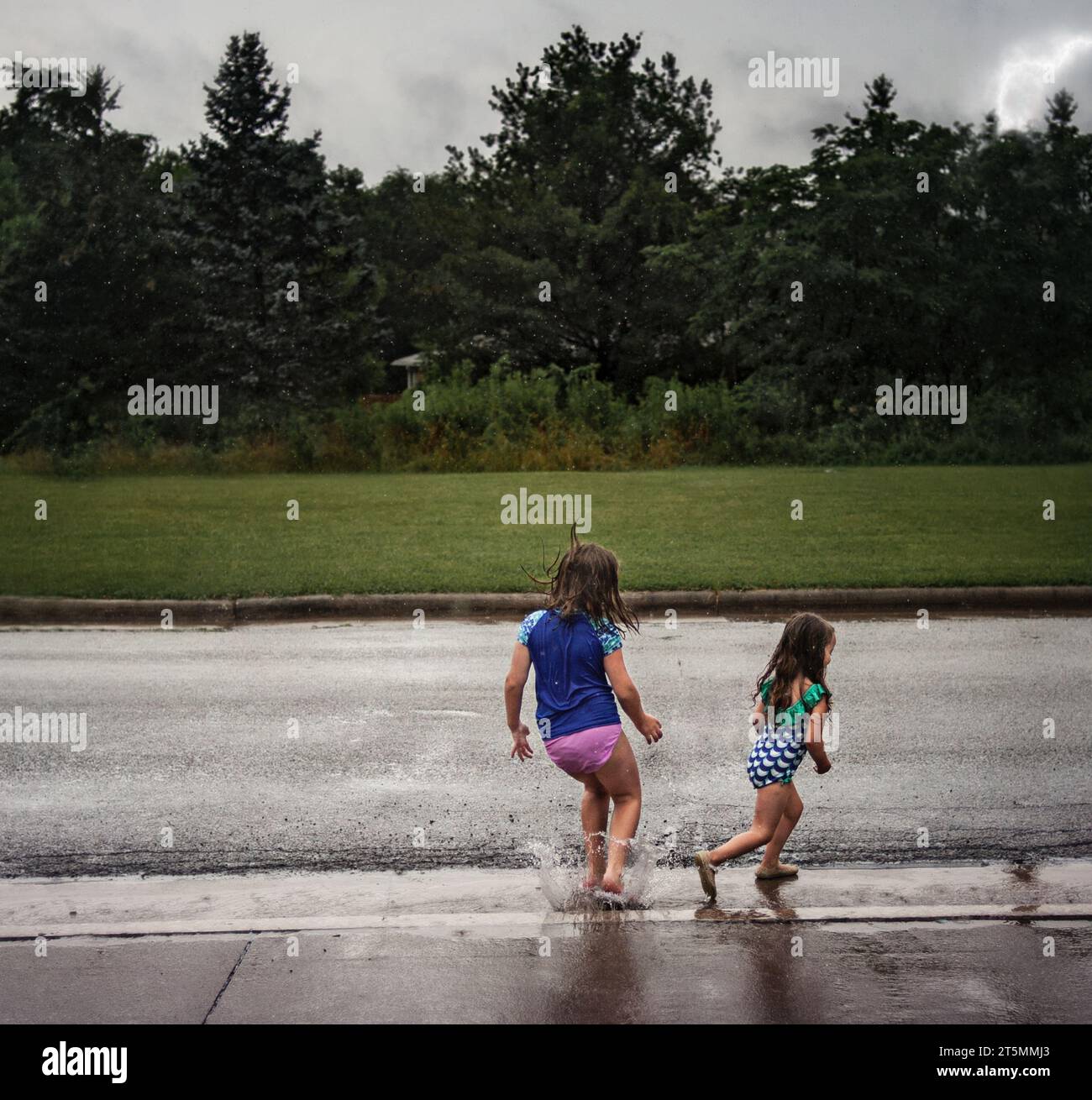 Young sisters splashing in the rain in summer Stock Photo - Alamy