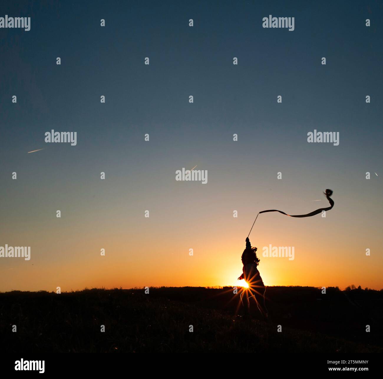 Silhouette of young child running with streamer at sunset Stock Photo ...