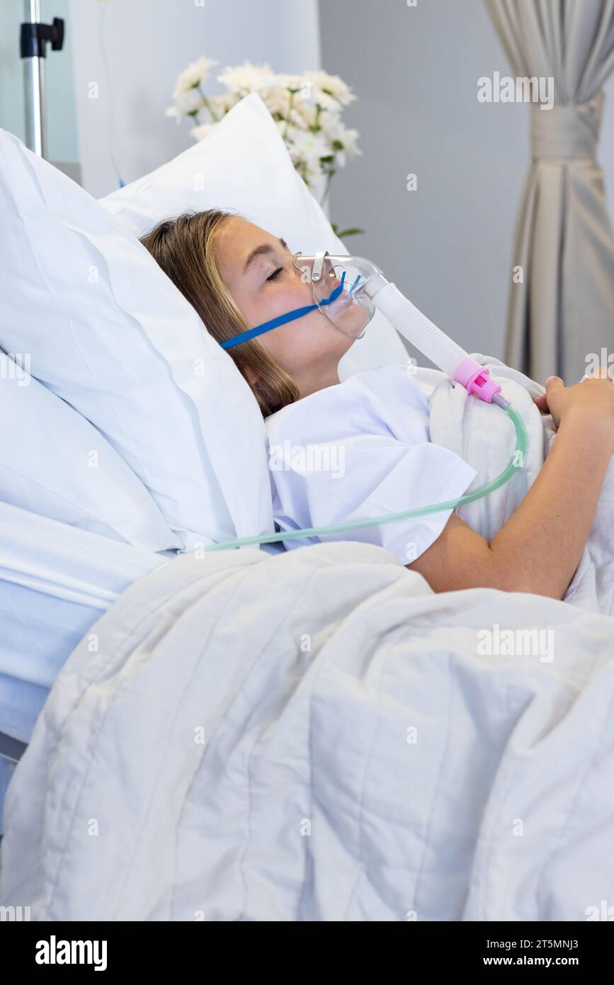 Caucasian girl patient wearing oxygen mask asleep in hospital bed, copy ...