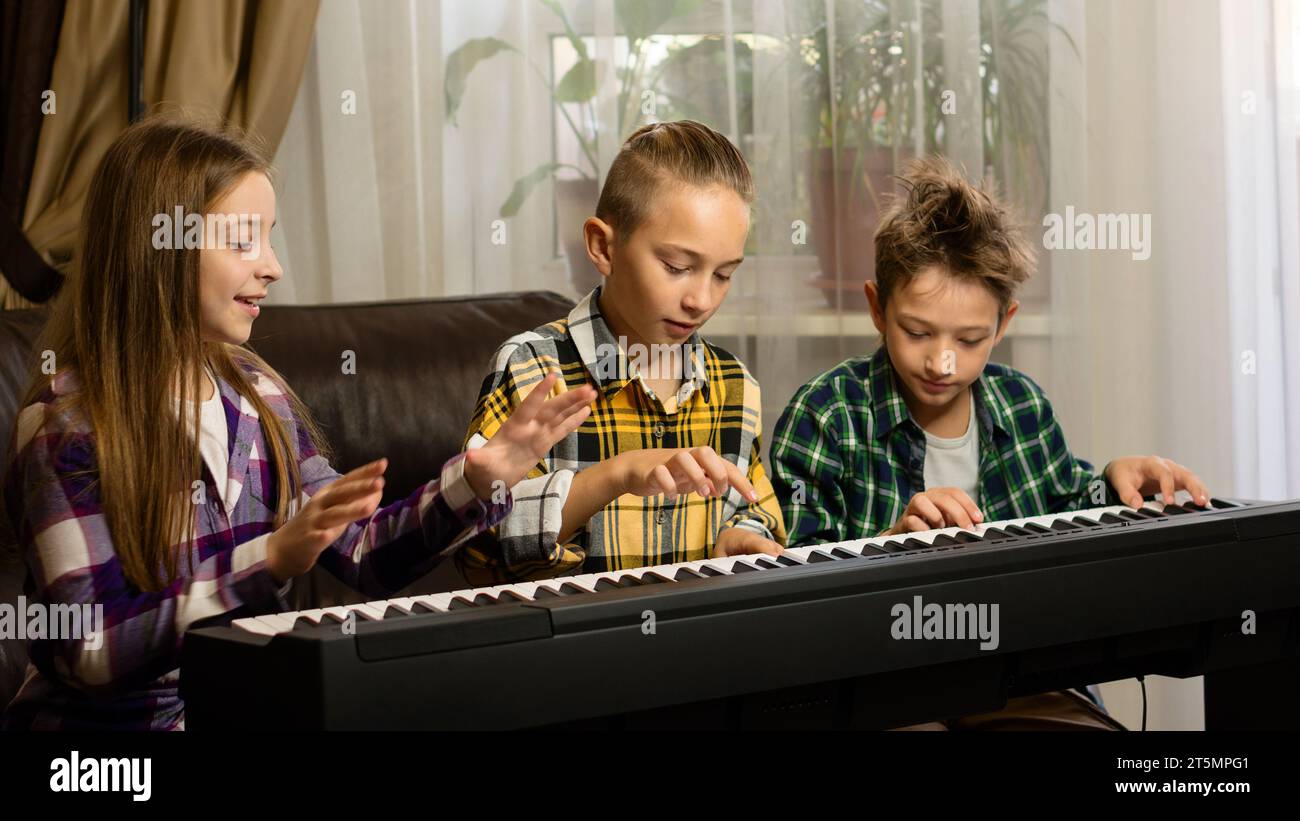 Three children engaged and enjoying playing the piano together in a ...