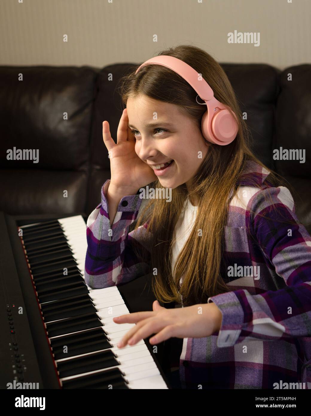 A girl smiles brightly while enjoying her piano lesson at home, wearing ...