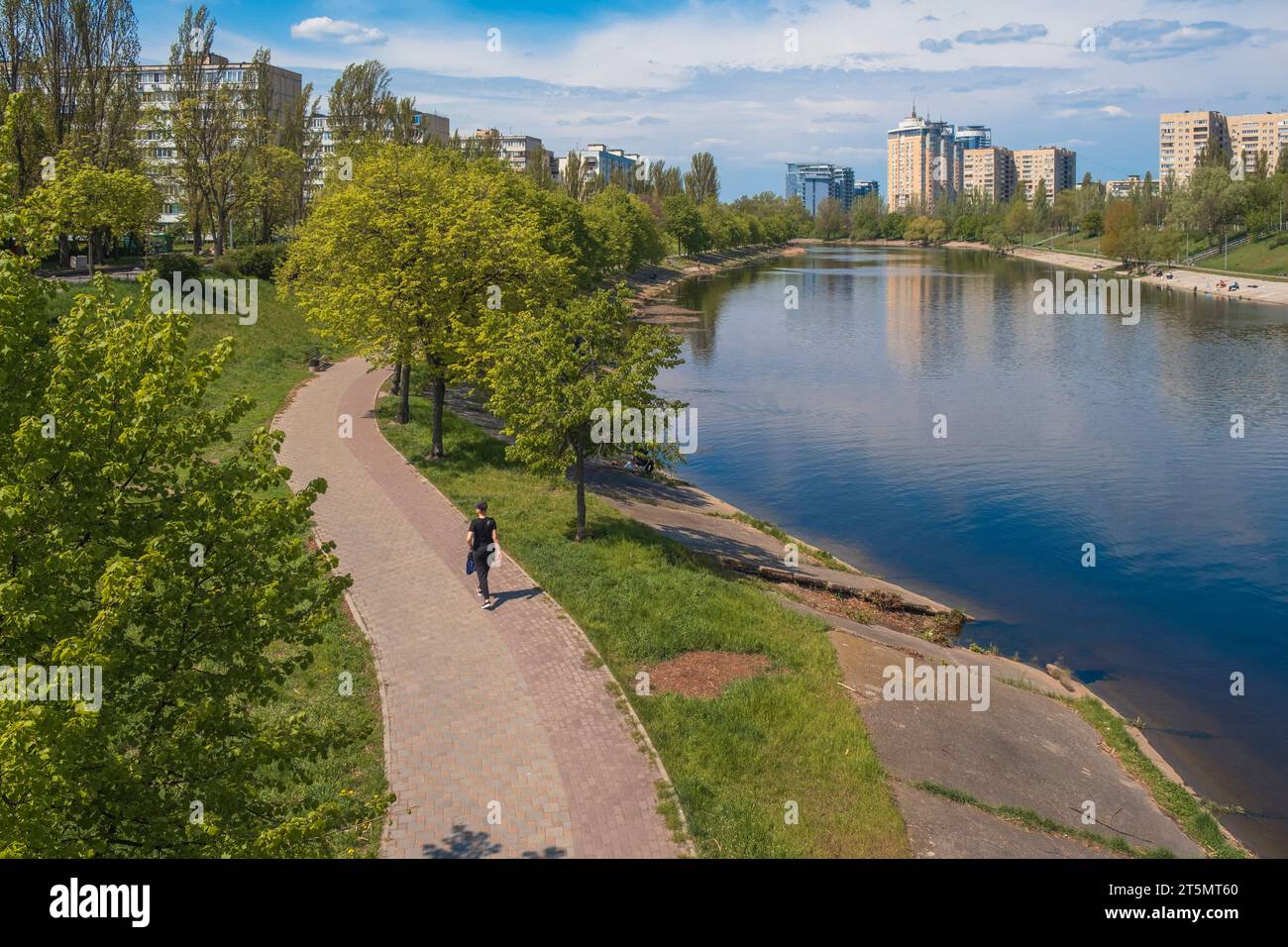 A woman on a pathway lined with lush greenery along a river Stock Photo ...