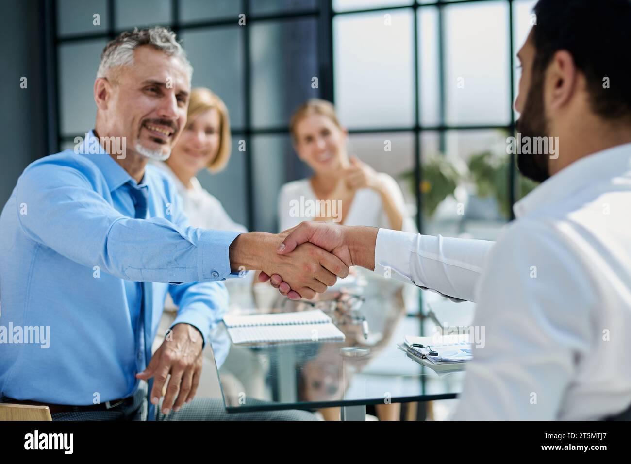 handshake of the boss and the employee sitting at the Desk in the ...