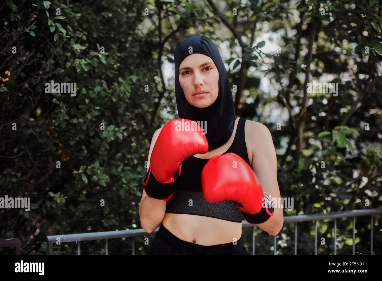 Muslim boxer woman in red boxing gloves and hijab standing outdoors ...