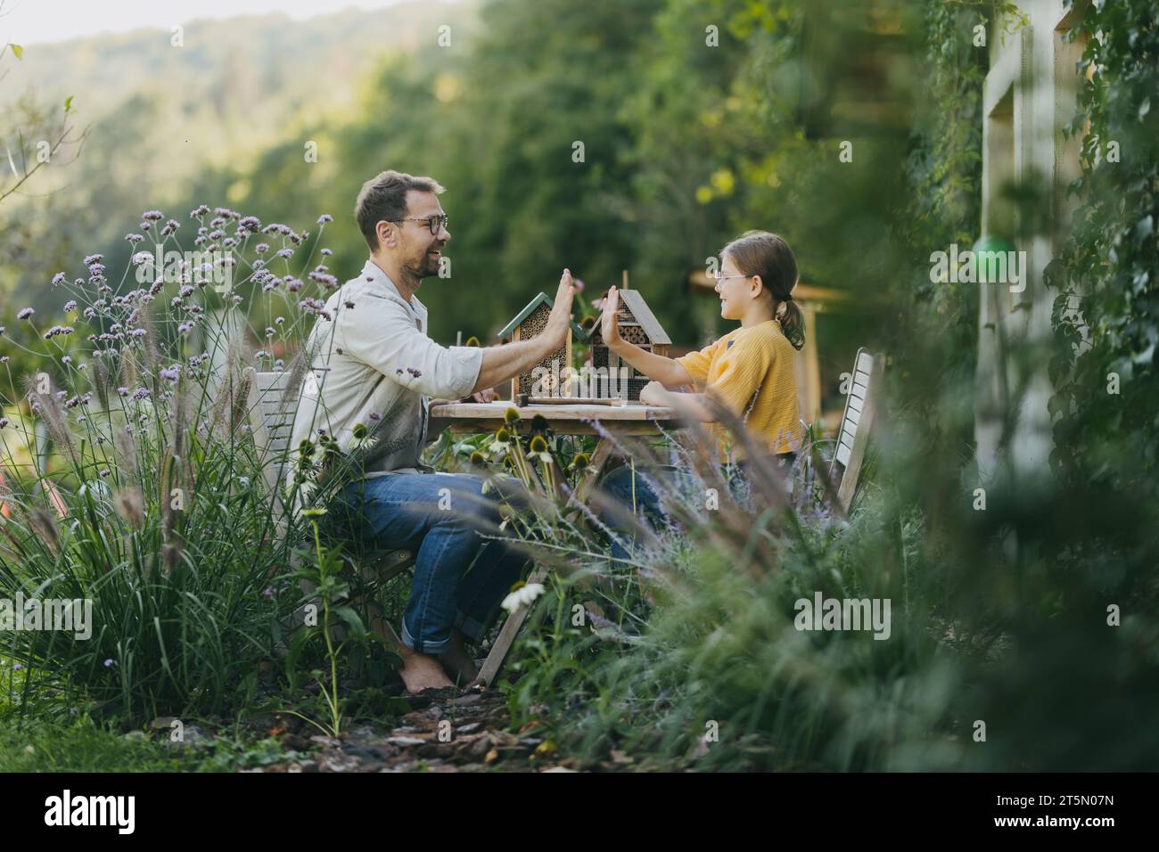Father with daughter making bug hotel, or insect house outdoors in the ...