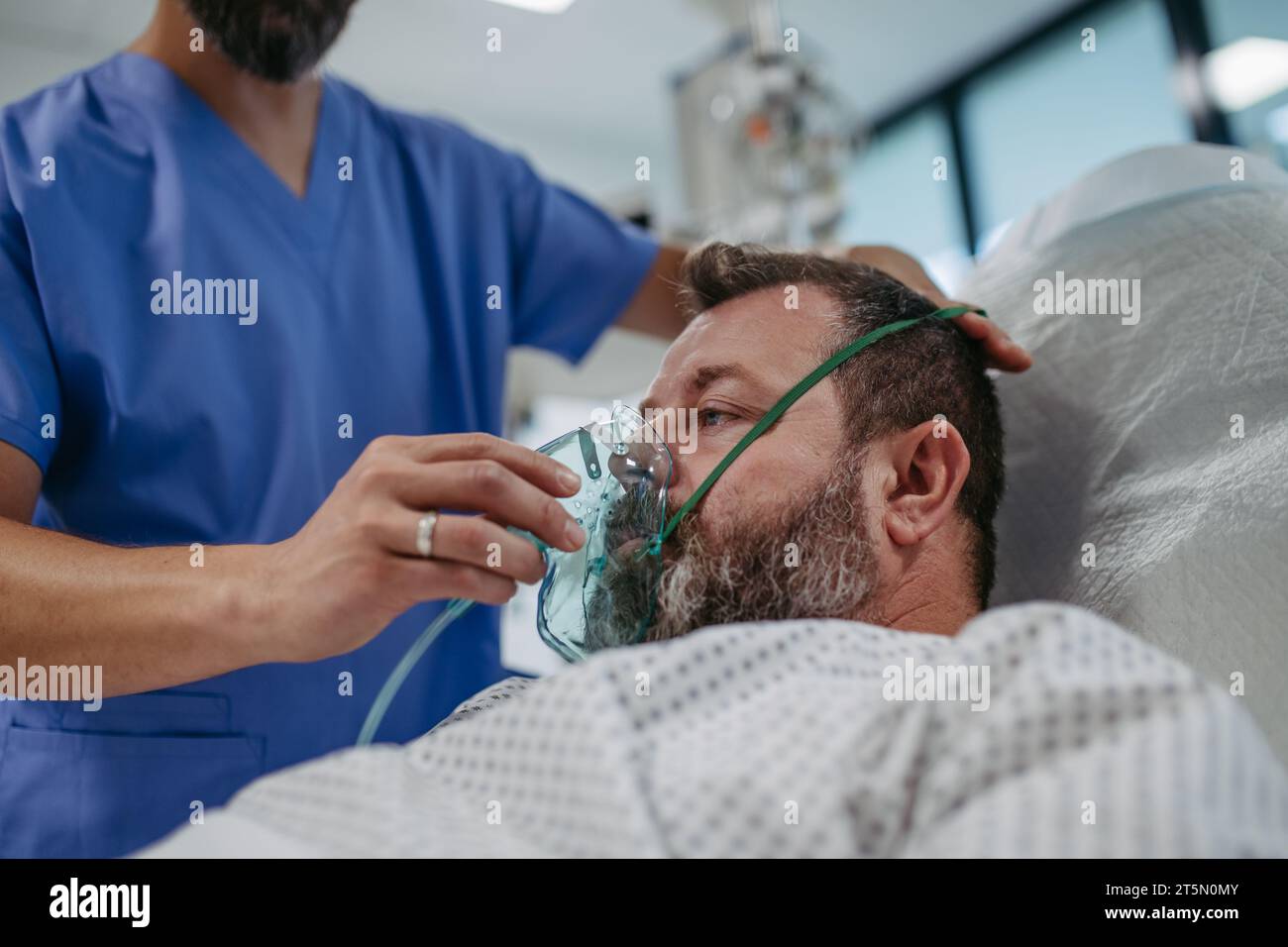 Nurse fitting oxygen mask on patient in hospital bed. Man in intensive ...