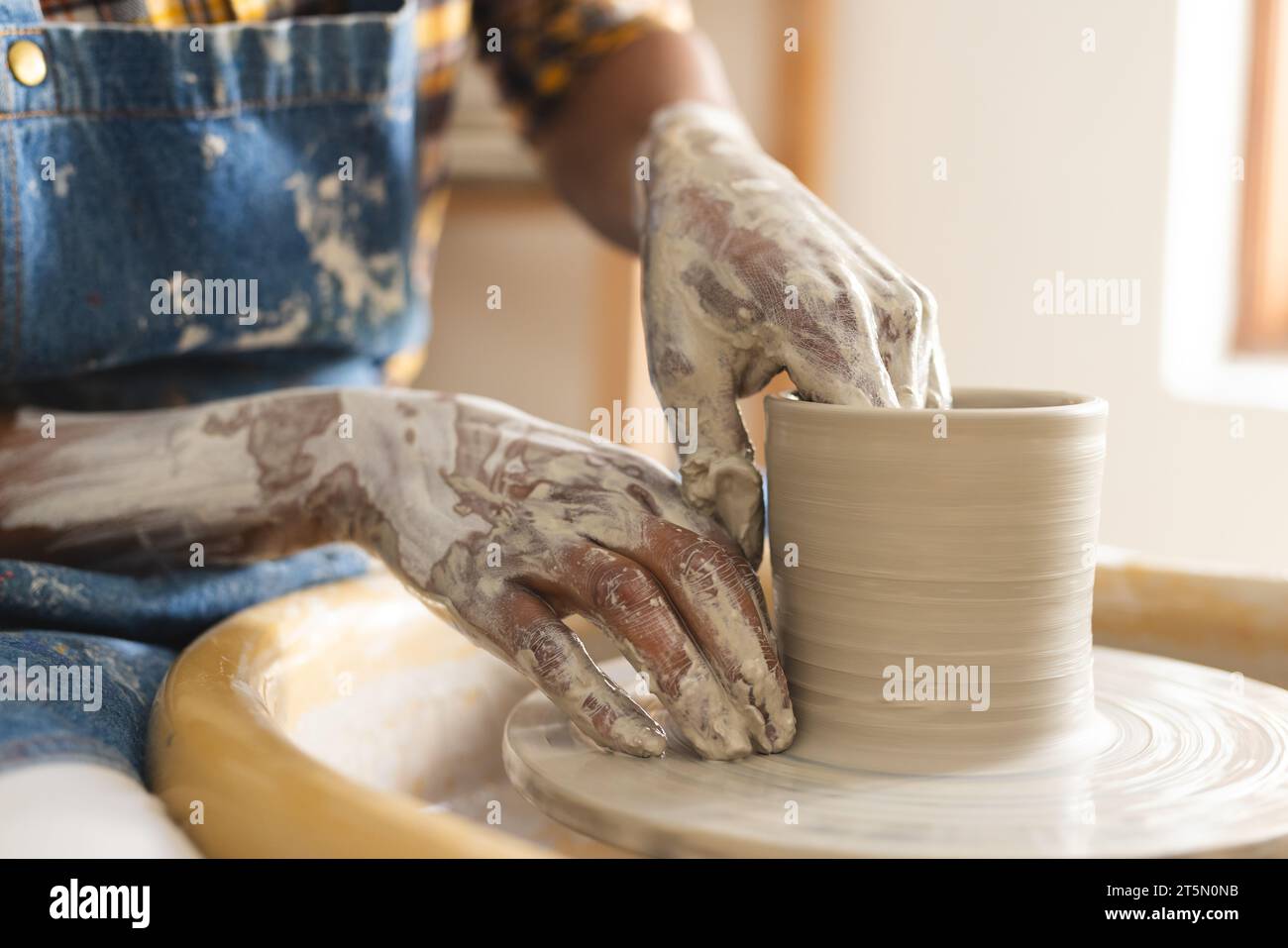 Hands of african american potter working on clay vase using potter's ...