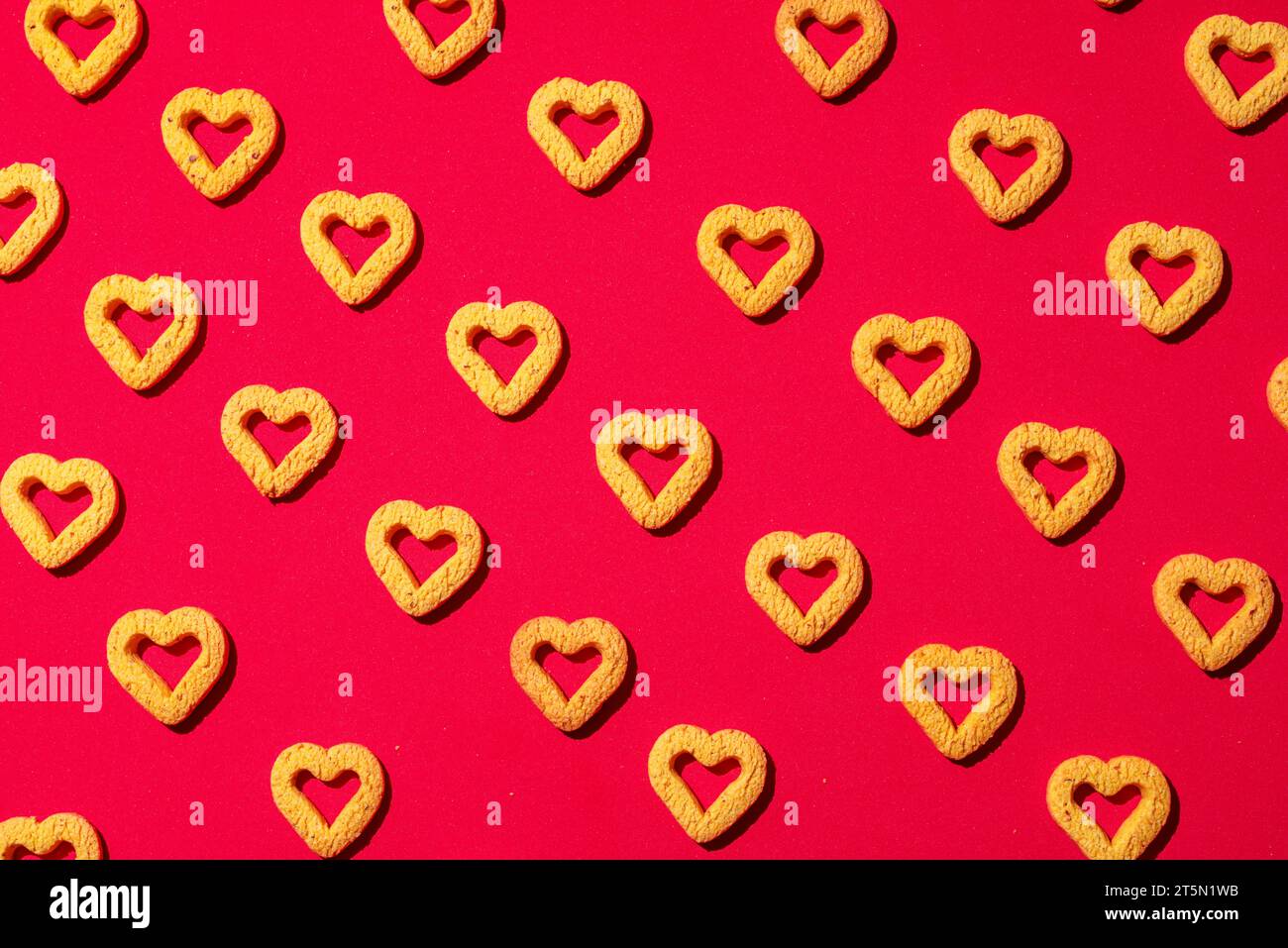 Small heart-shaped cookies on a red background. A beautiful background ...