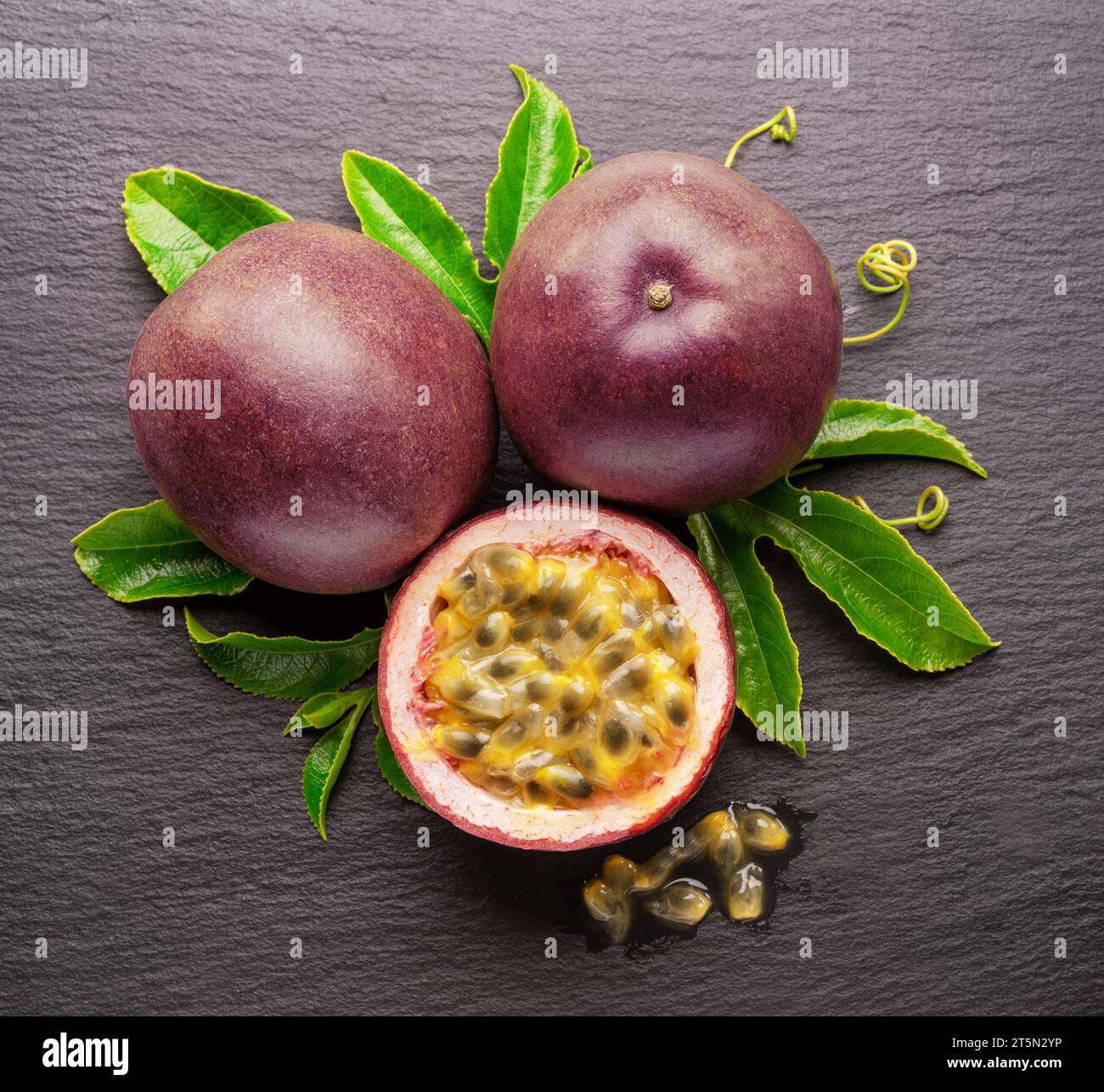 Dark purple passion fruits and half of maracuya fruit isolated on slate ...