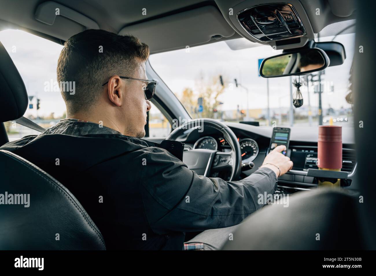 A man uses a smartphone installed in the holder while driving a car ...