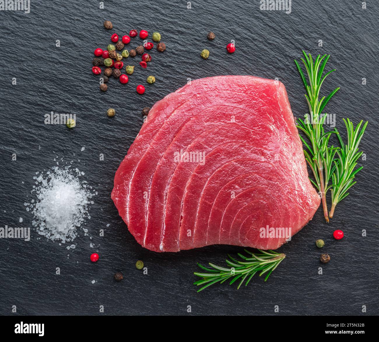 Raw tuna fish steak on natural stone black slate serving plate. Top ...