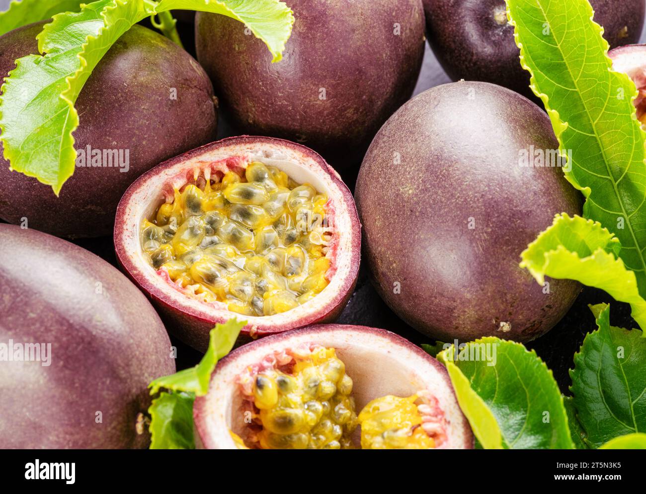 Ripe passion fruits with passion fruit seeds and passionfruit leaves on ...