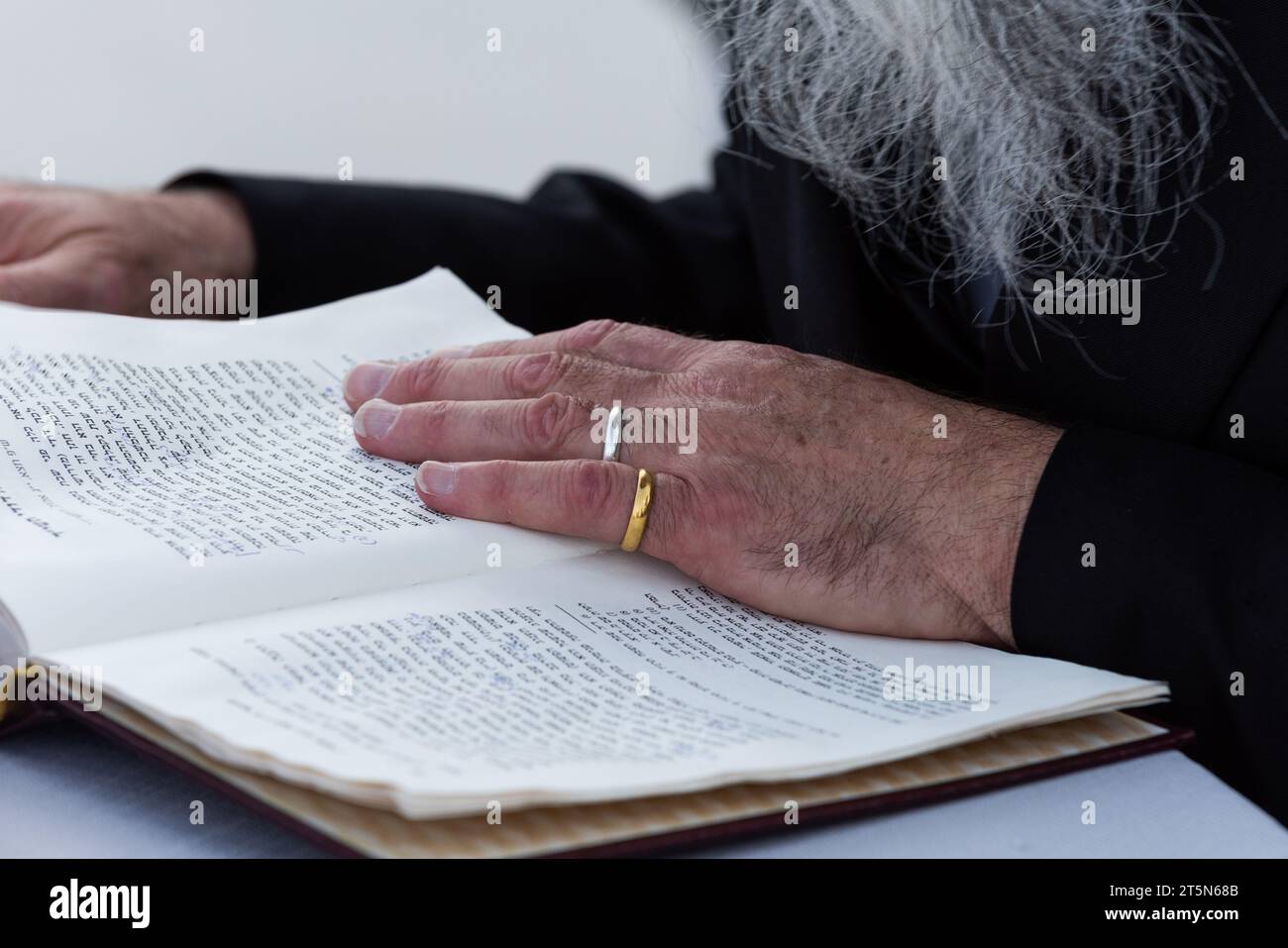 A man places the rings of the bride and groom on his fingers for ...