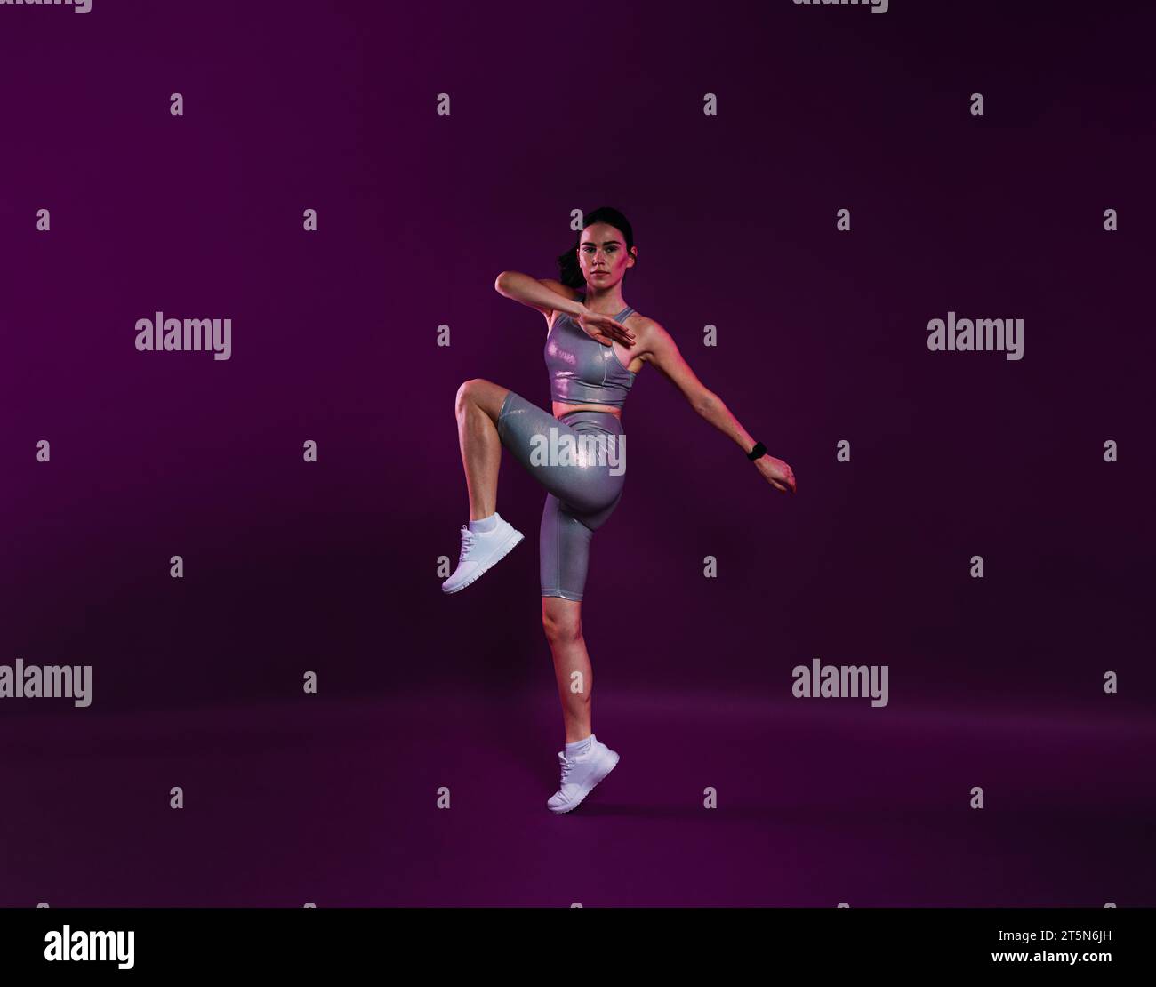 Full length of slim healthy woman warming up over a magenta background ...