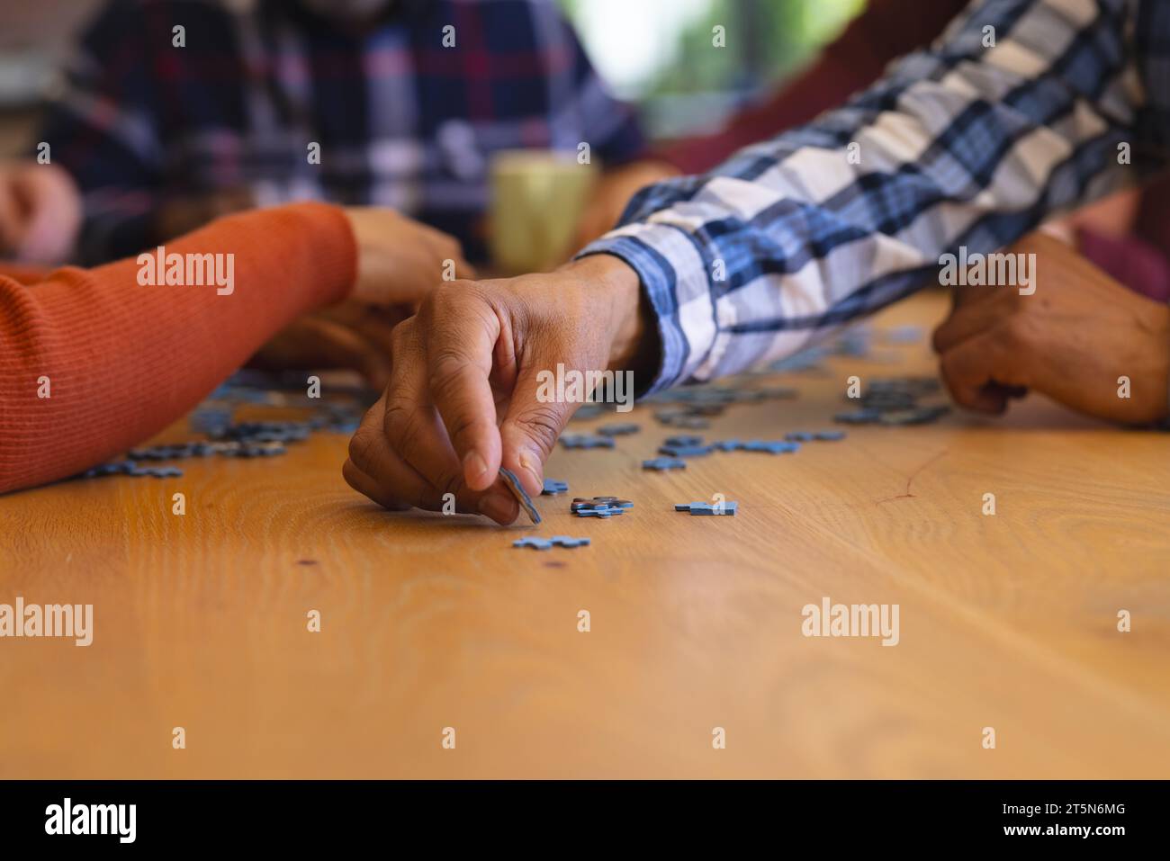 Hands of diverse group of senior friends playing with jigsaw puzzles in ...