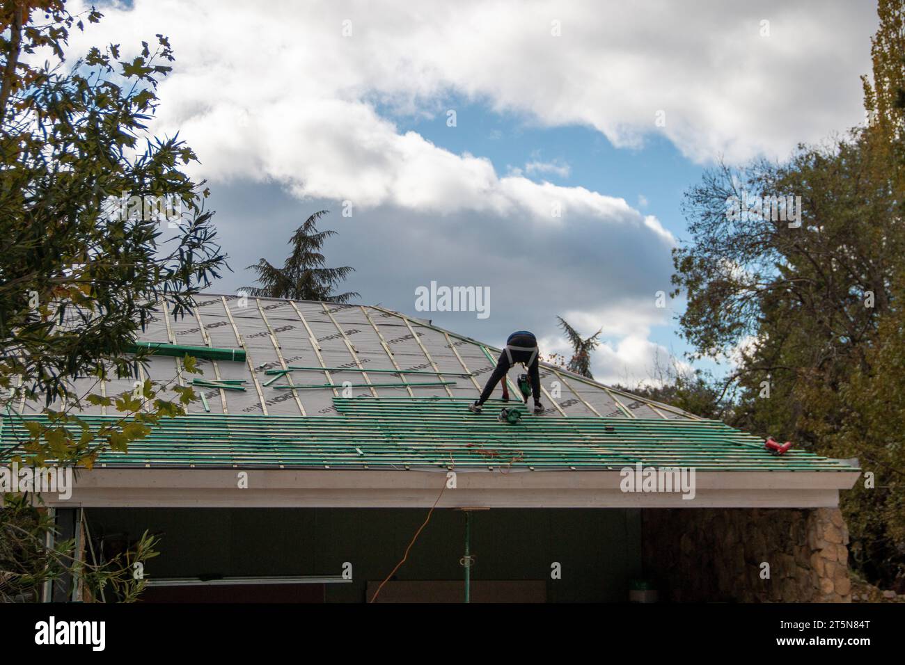 Worker with harness building the roof of a house Stock Photo - Alamy