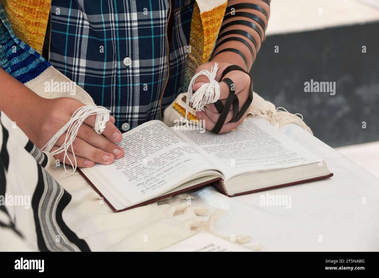 A Jewish man grasps the strings of his tallit or tzitzit while reciting ...