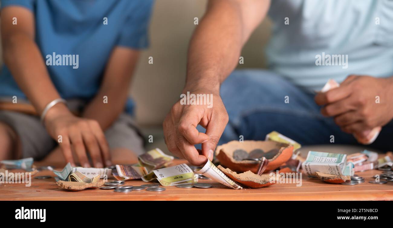 Close up shot, Indian father and son taking money by breaking clay ...