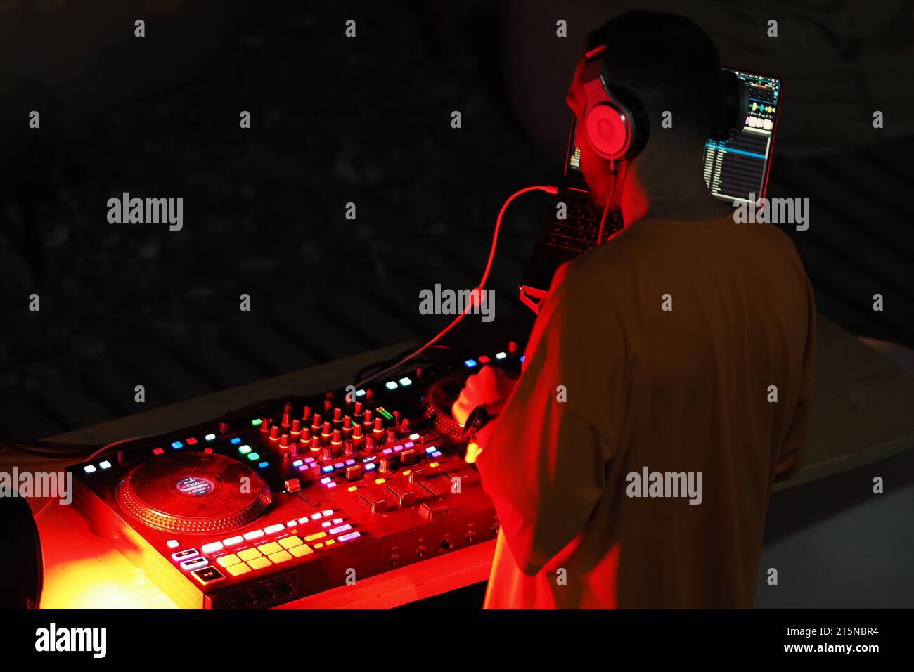 DJ wearing headphones stands at music console in nightclub Stock Photo ...