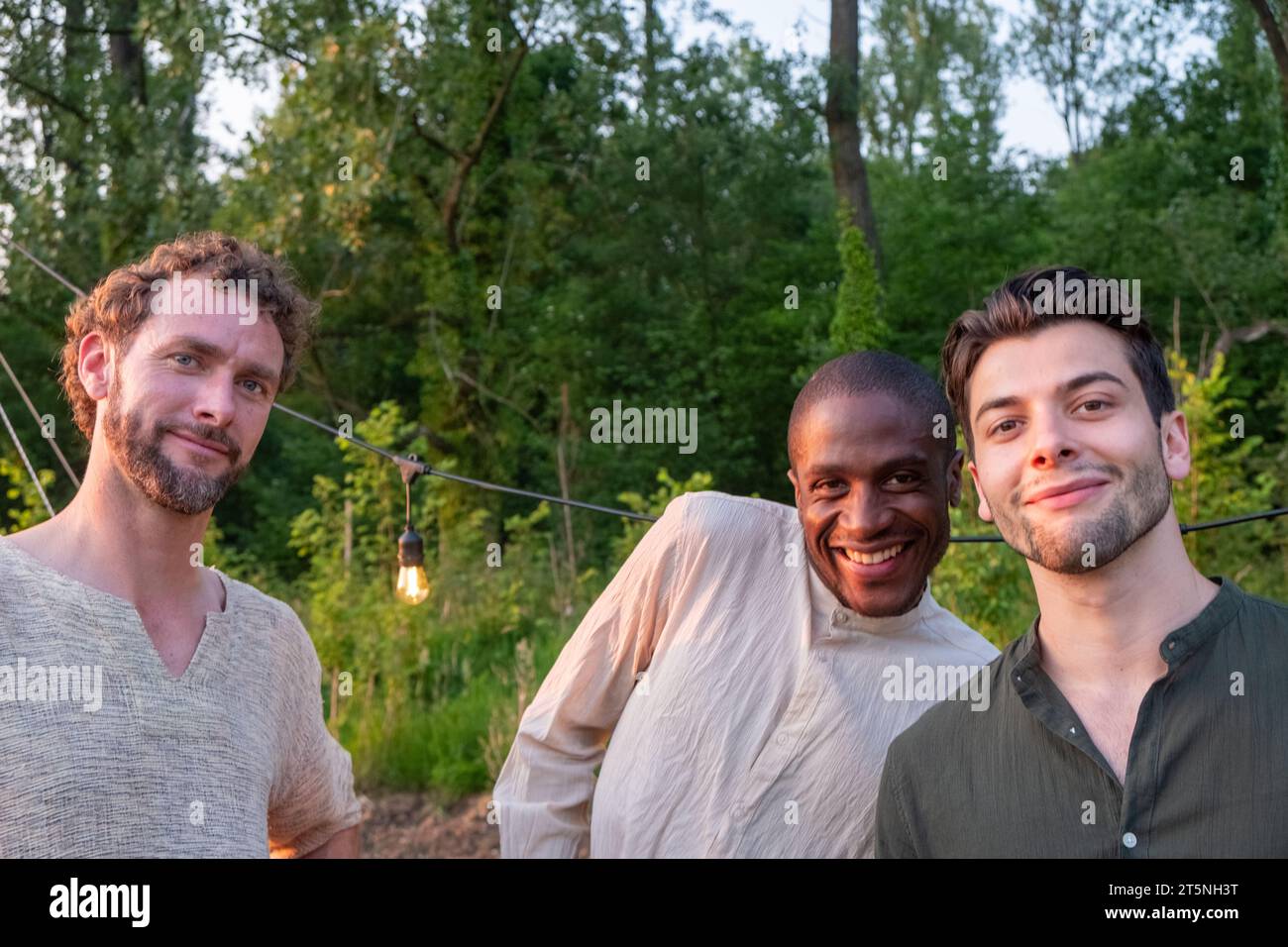 In the vibrant backdrop of an outdoor party, three male friends from ...