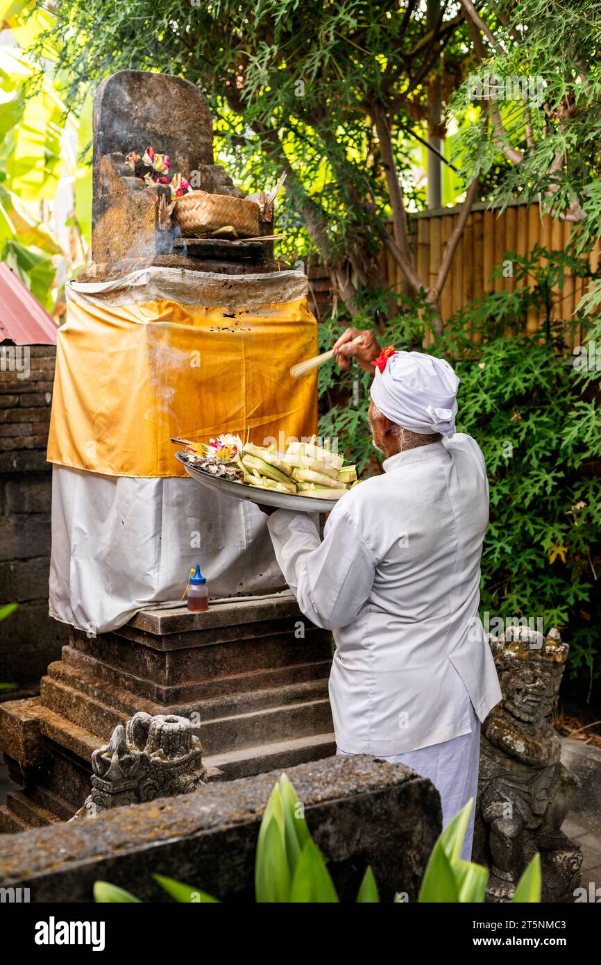 Balinese priest sprinkling holy water over offerings Stock Photo - Alamy