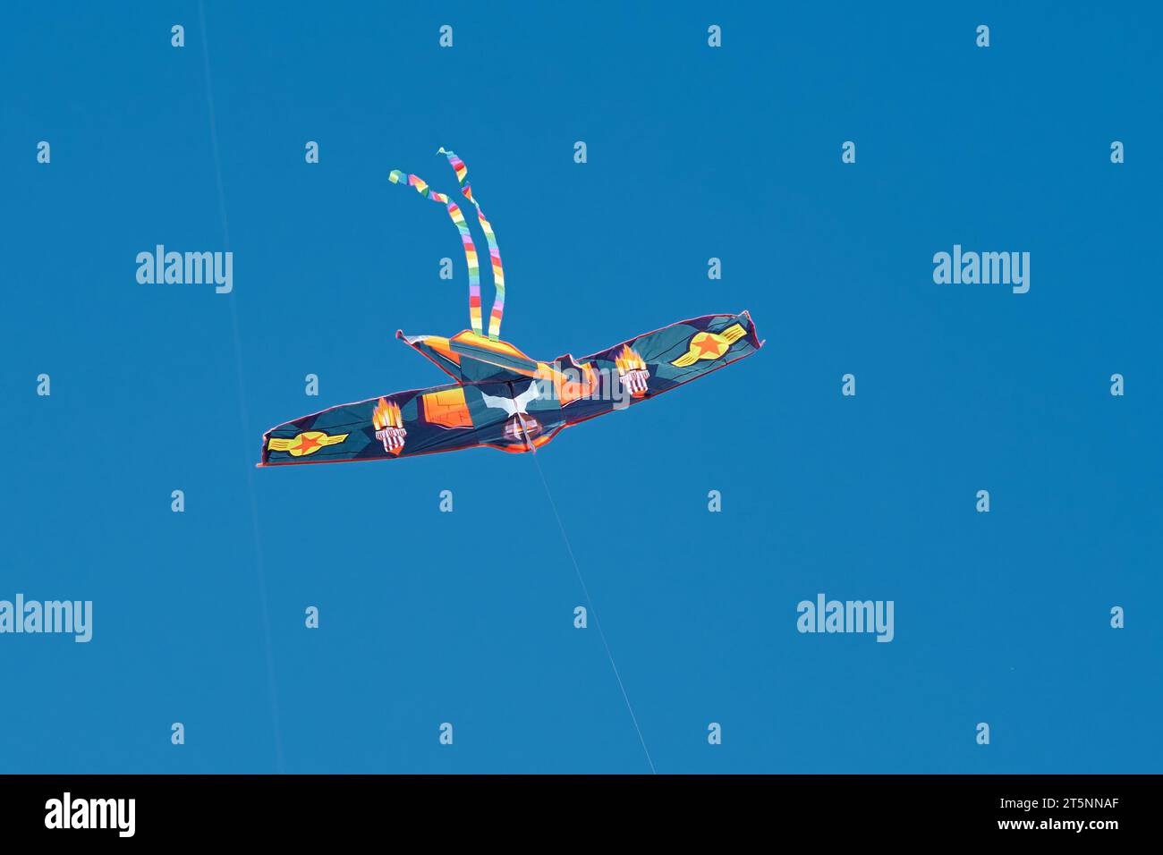 An outdoor kite flying festival. Kites are launched into the blue sky ...