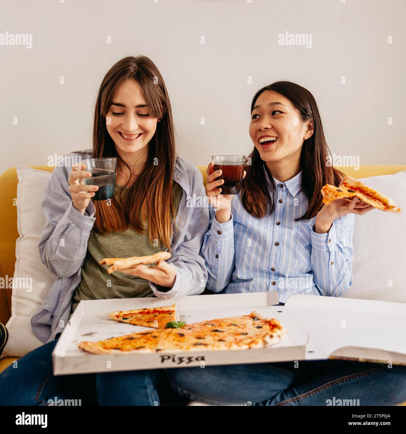 Laughing relaxing girls enjoying pizza Stock Photo - Alamy