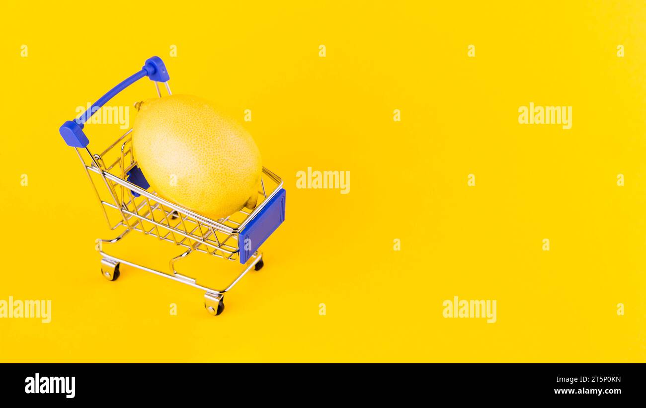 Lemon inside shopping cart against yellow background Stock Photo - Alamy
