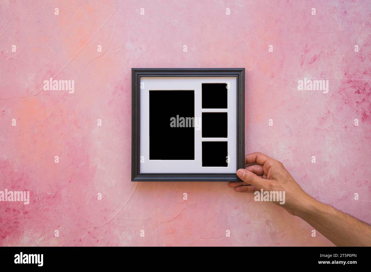 Man s hand placing picture frame painted pink wall Stock Photo - Alamy