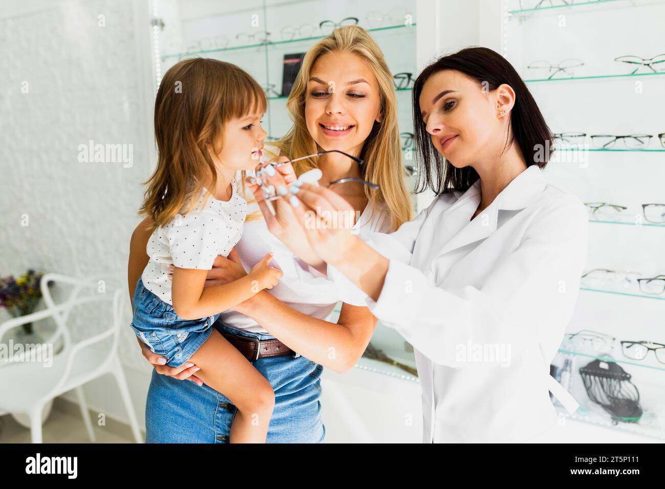 Optician showing little girl glasses frame Stock Photo - Alamy