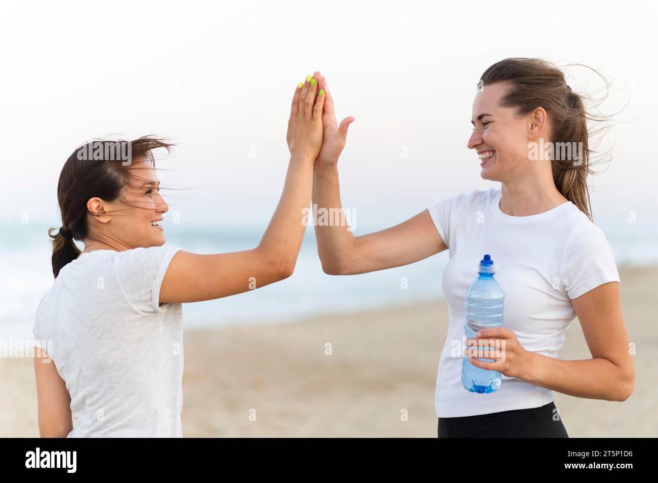 Side view two women high fiving each Stock Photo - Alamy