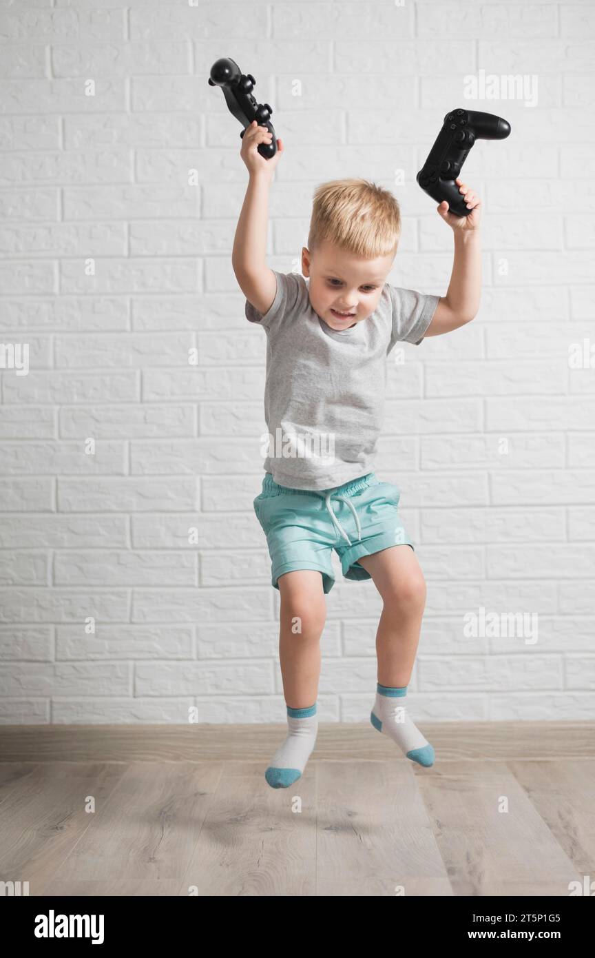 Smiley boy with joysticks hand jumping Stock Photo - Alamy