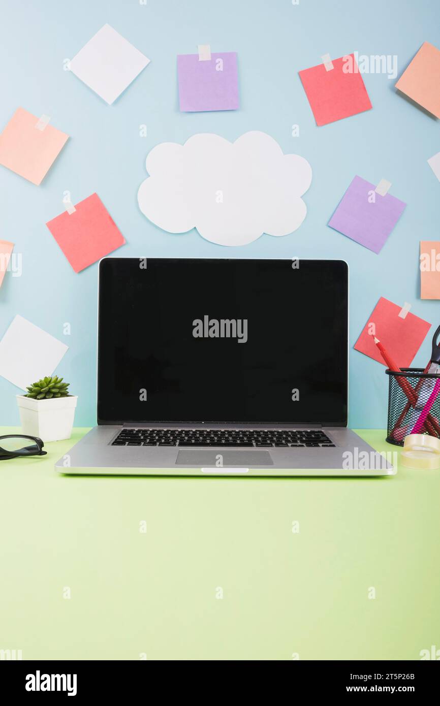 Wall with cloud paper adhesive notes laptop with blank black screen ...