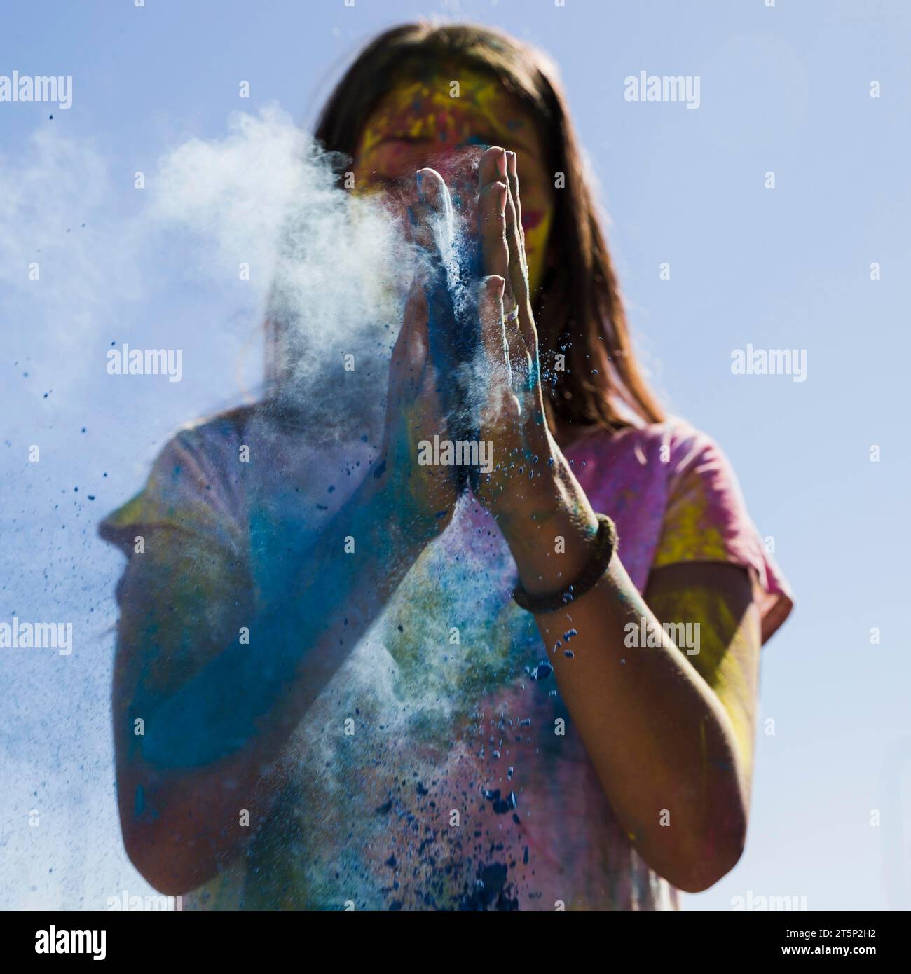 Young woman dusting blue holi color with hands Stock Photo - Alamy