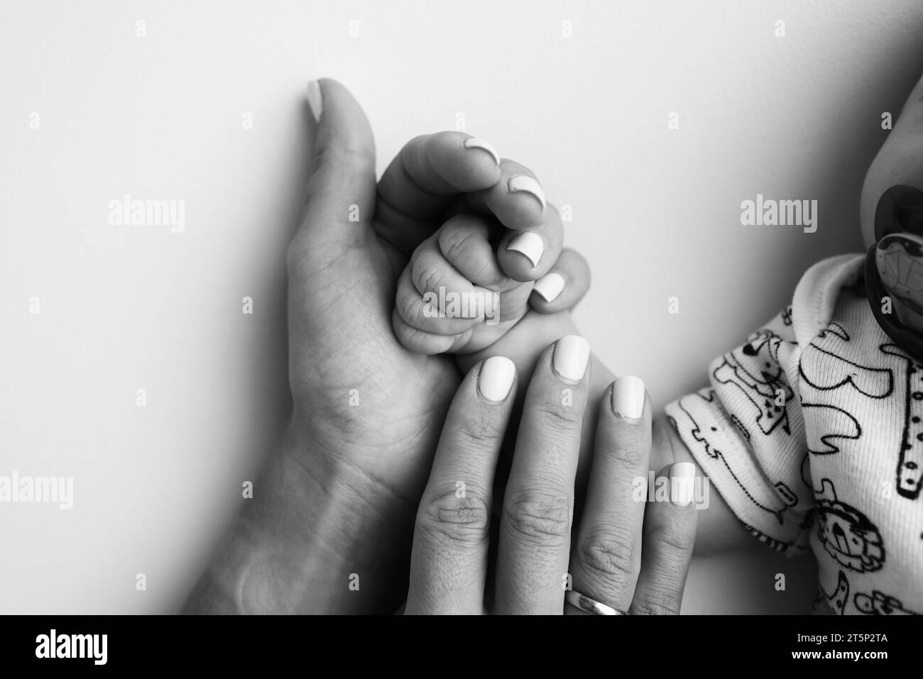 Parents' hands hold the fingers of a newborn baby. The hand of mother ...