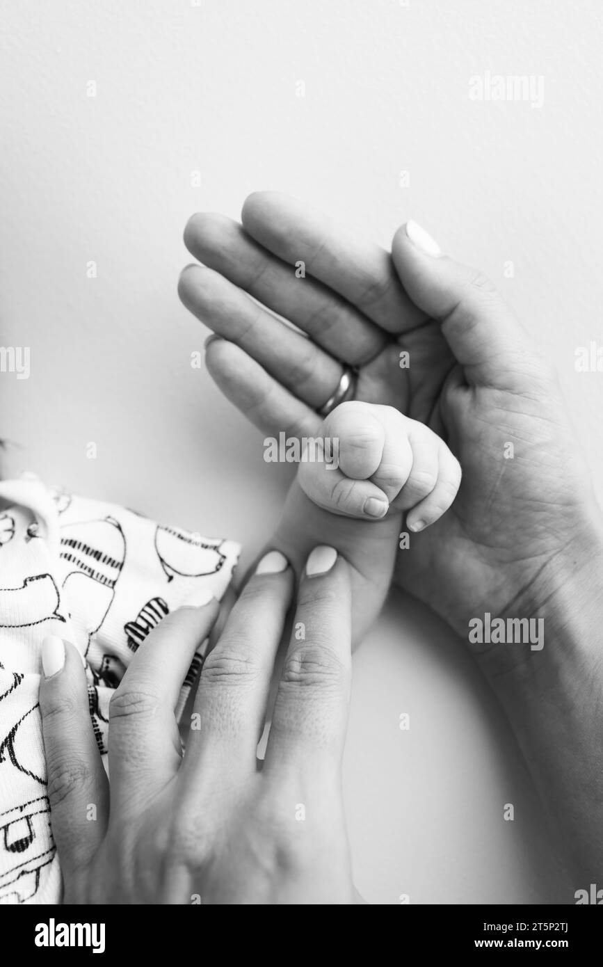 Parents' hands hold the fingers of a newborn baby. The hand of mother ...