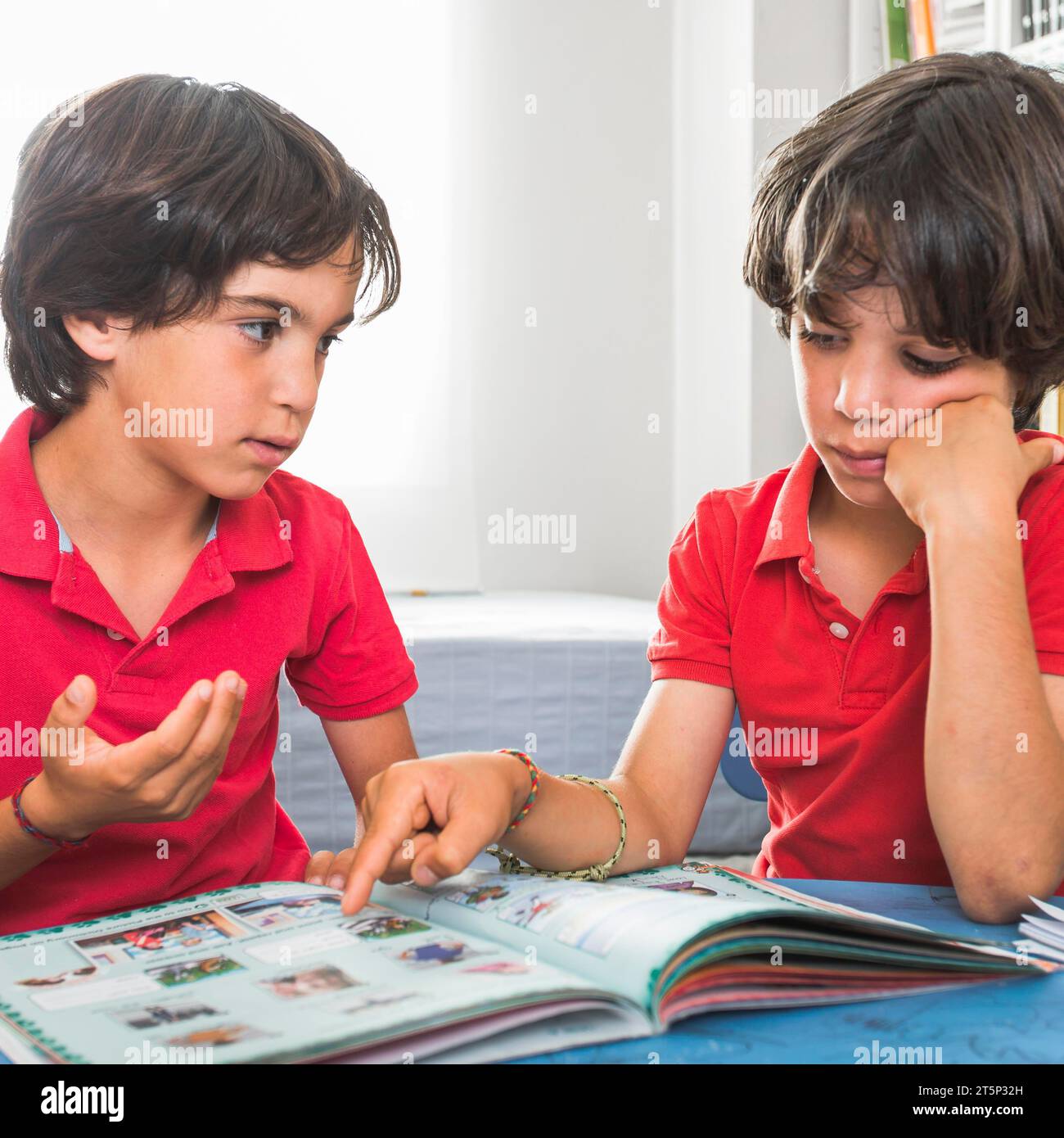 Brothers talking sitting with book Stock Photo - Alamy