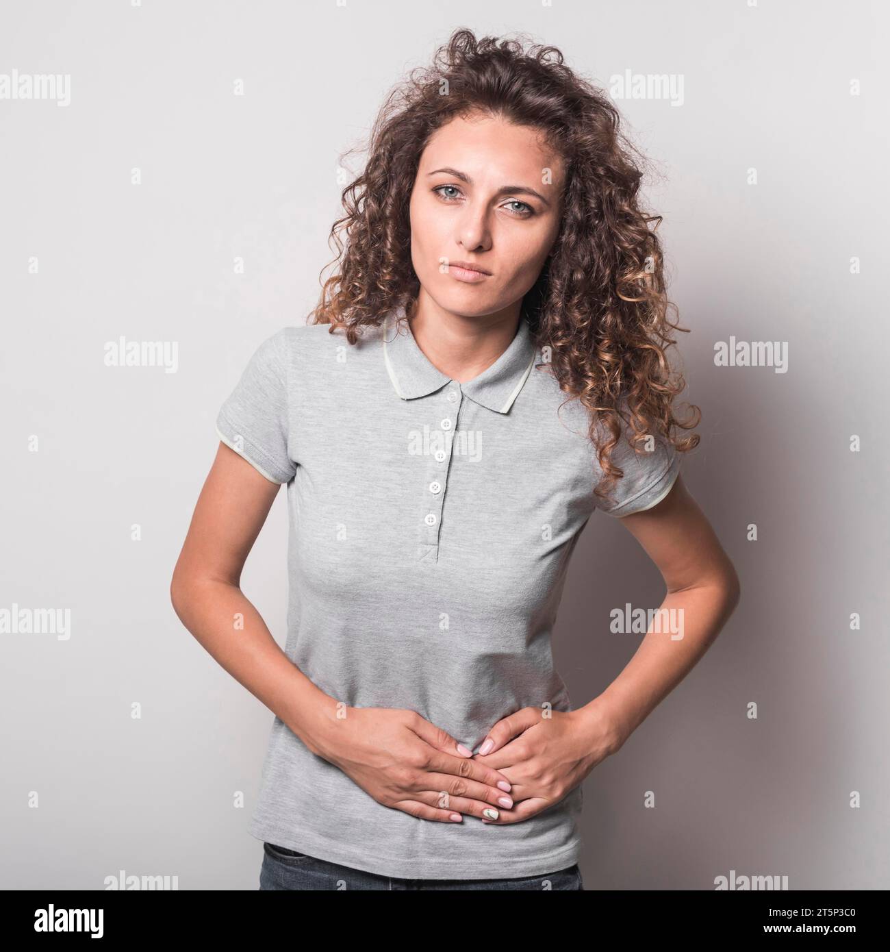 Close up young woman suffering from stomach ache against gray ...