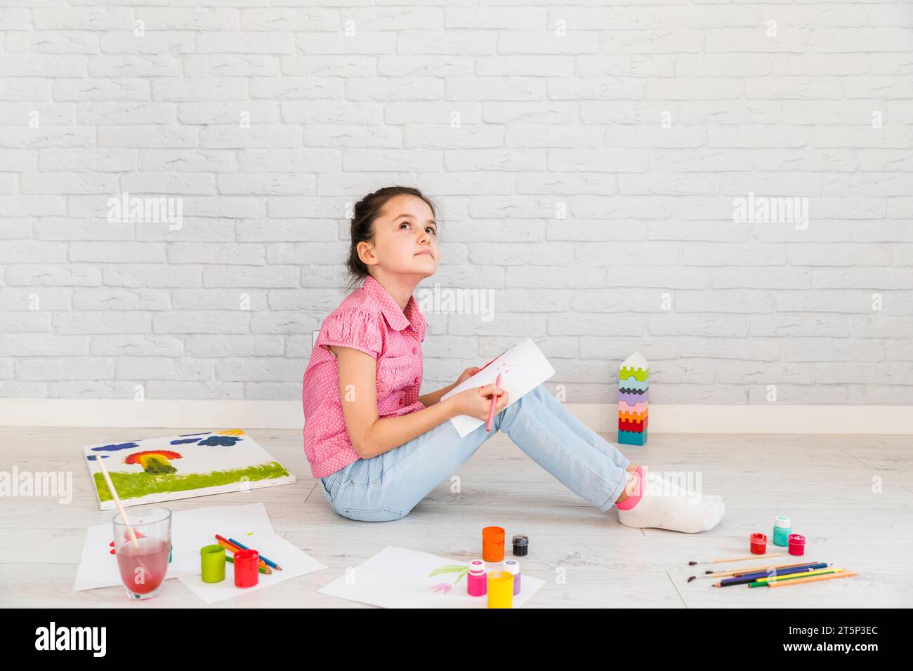 Contemplated girl sitting floor drawing white paper with colored pencil ...