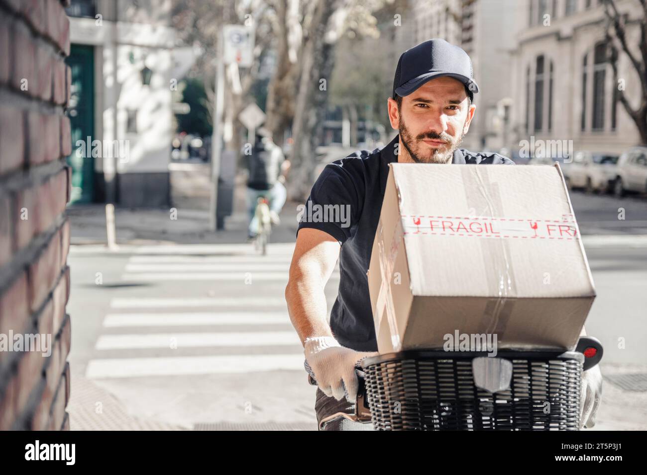 Delivery man riding bicycle with parcel Stock Photo - Alamy