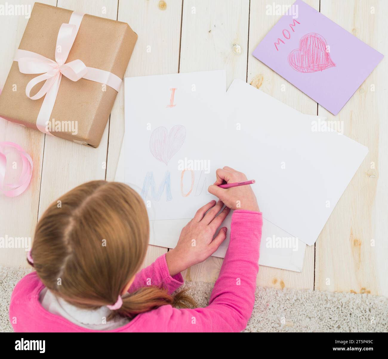 Girl drawing i love mom paper sheet Stock Photo - Alamy