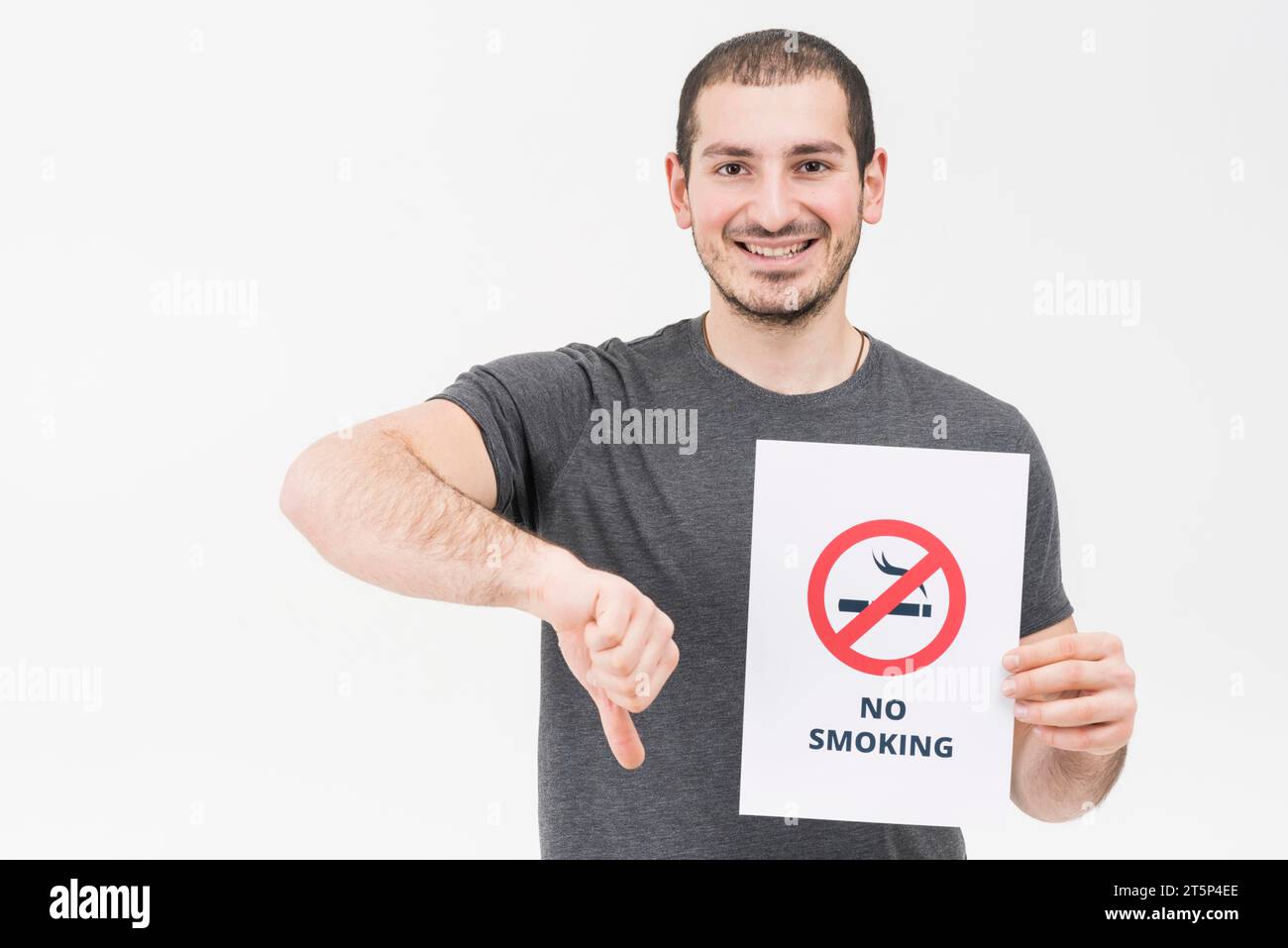 Happy young man holding no smoking sign showing thumb down isolated ...