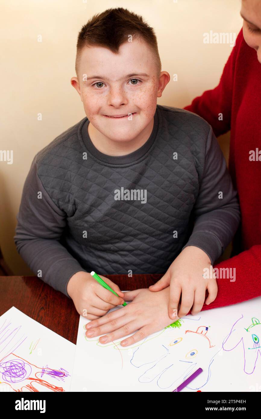 Happy boy with down syndrome drawing Stock Photo - Alamy