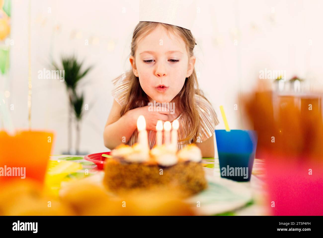 Girl paper crown blowing candles Stock Photo - Alamy