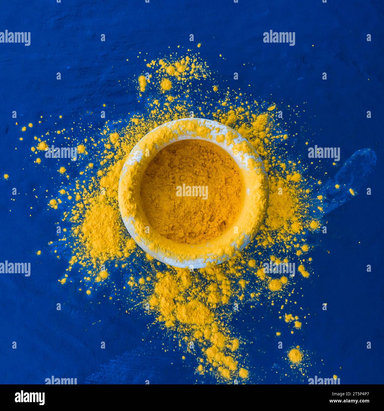 Indian holi festival yellow color bowl blue backdrop Stock Photo - Alamy