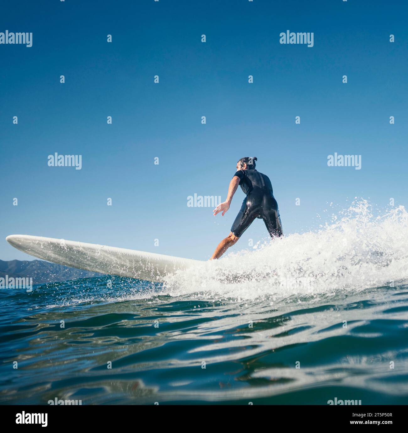 Man riding his surfboard side view Stock Photo - Alamy