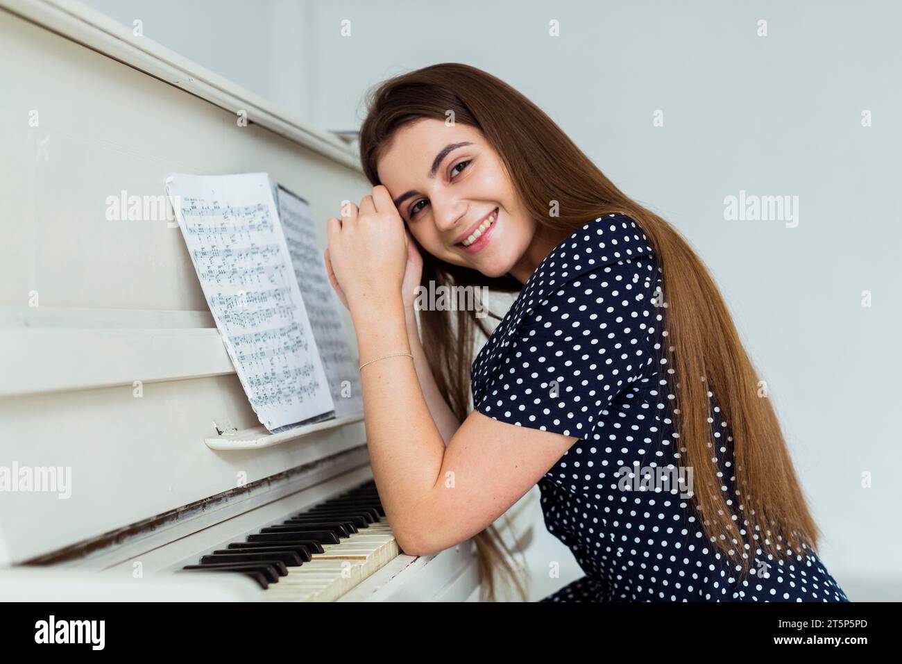 Portrait smiling young woman leaning piano looking camera Stock Photo ...